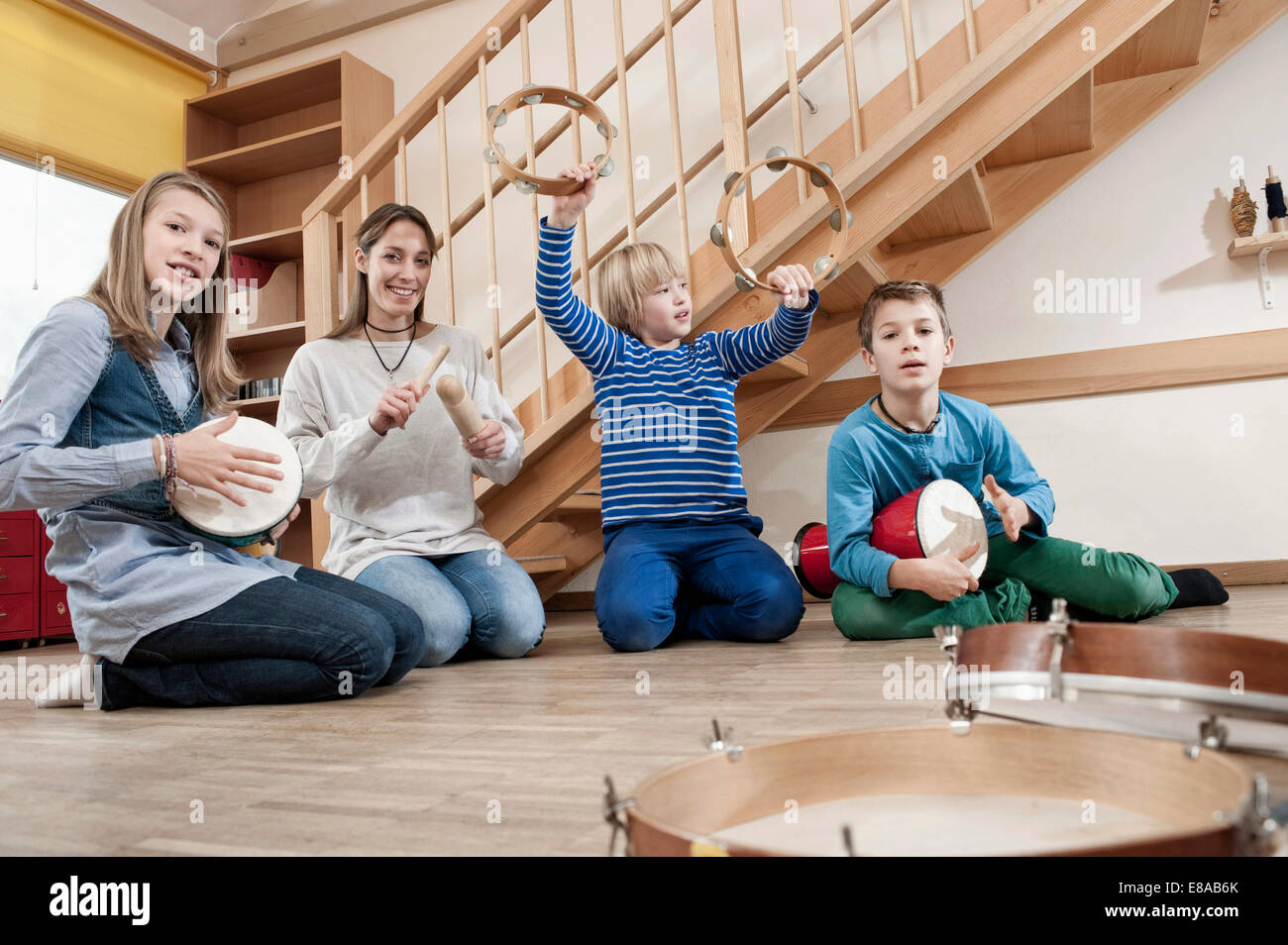 Group of female childcare assistant and three children drumming Stock ...