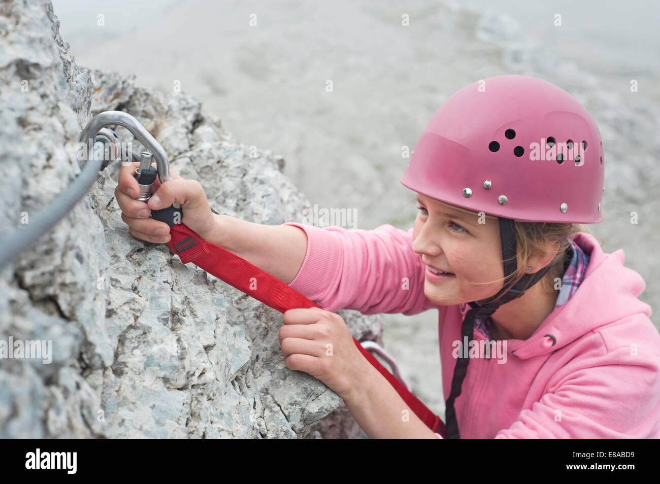 Teenage girl climbing attaching carabiner to rope Stock Photo - Alamy