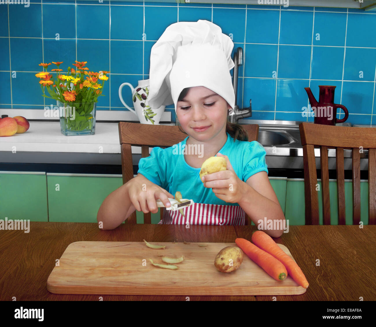 Girl in chef hat peels potatoes and carrots in kitchen Stock Photo - Alamy
