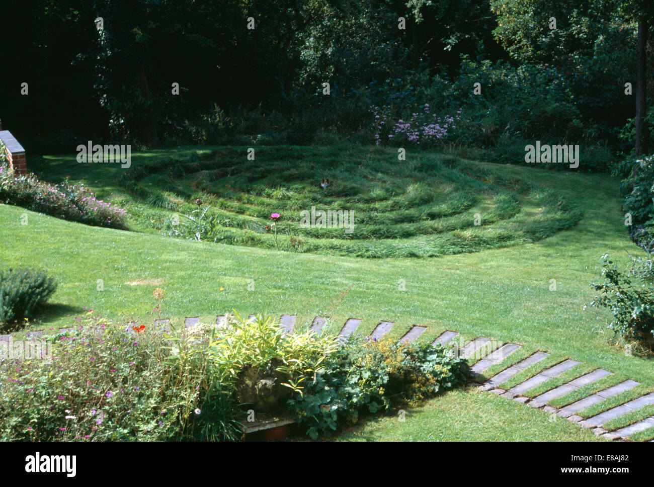 Paved path in lawn above long grass circle in sunken mown lawn in ...
