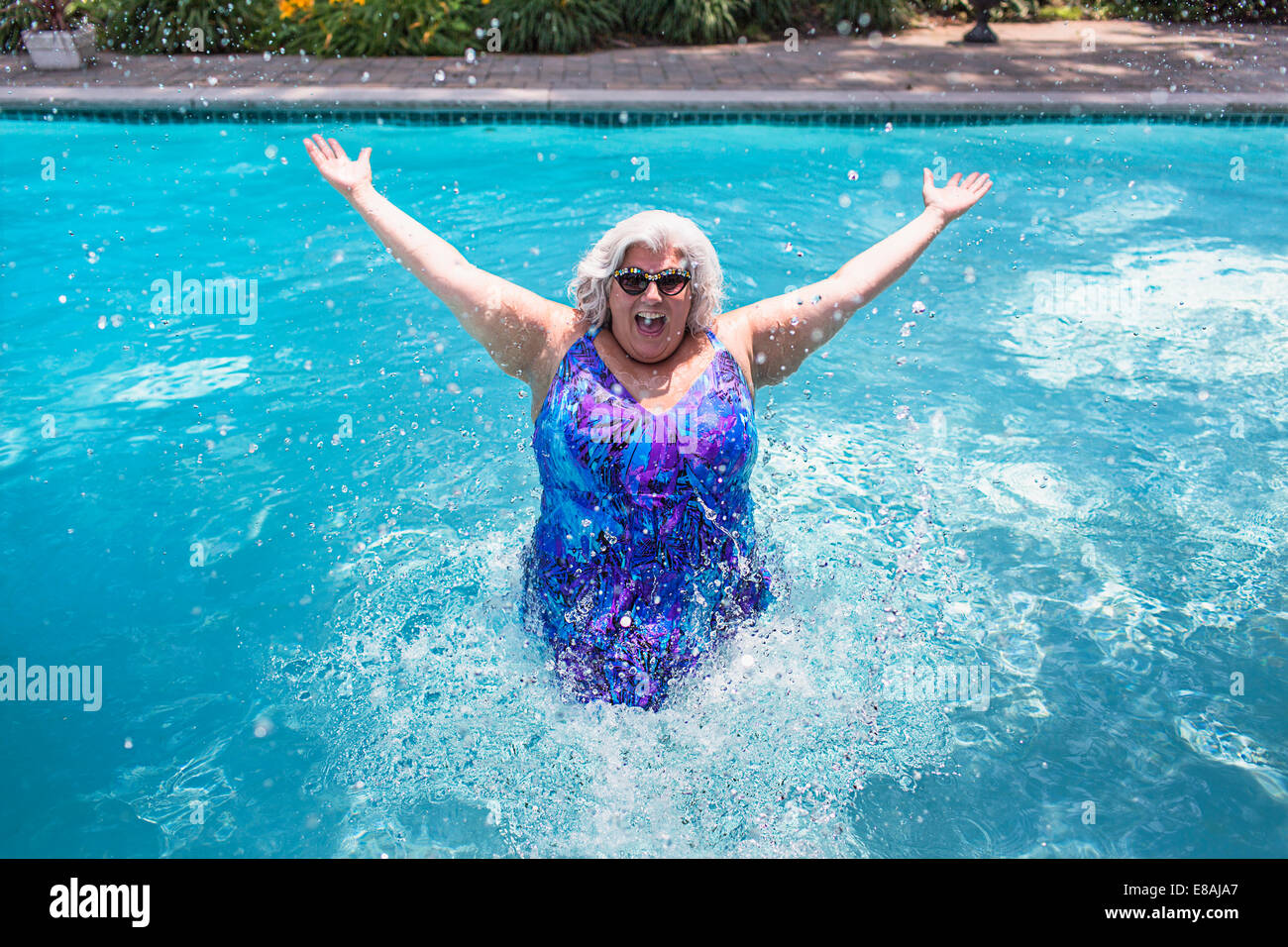 Portrait of mature woman splashing about in swimming pool Stock Photo ...