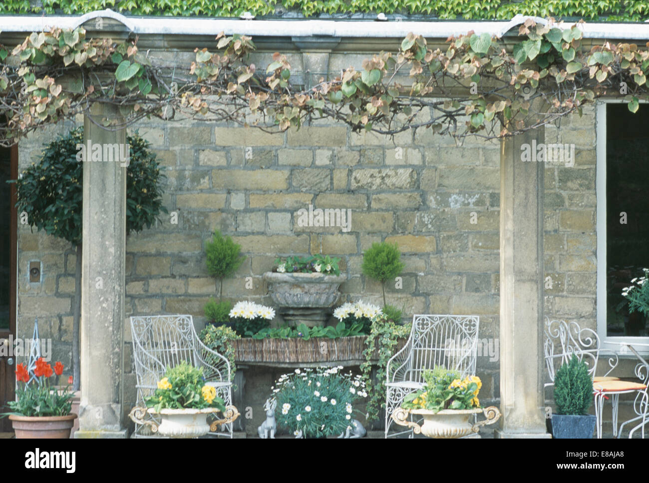 White metal chairs on country house terrace with stone columns and ...