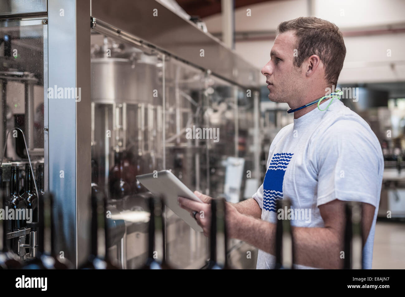 Young man working on production line with digital tablet in bottling ...