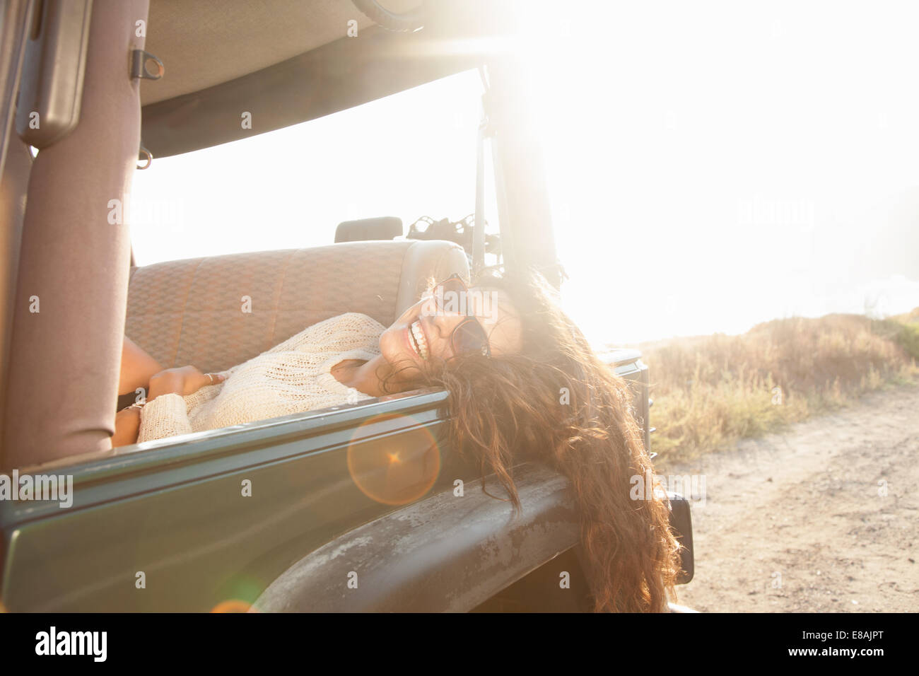 Portrait of young woman reclining in back seat of jeep at coast, Malibu ...