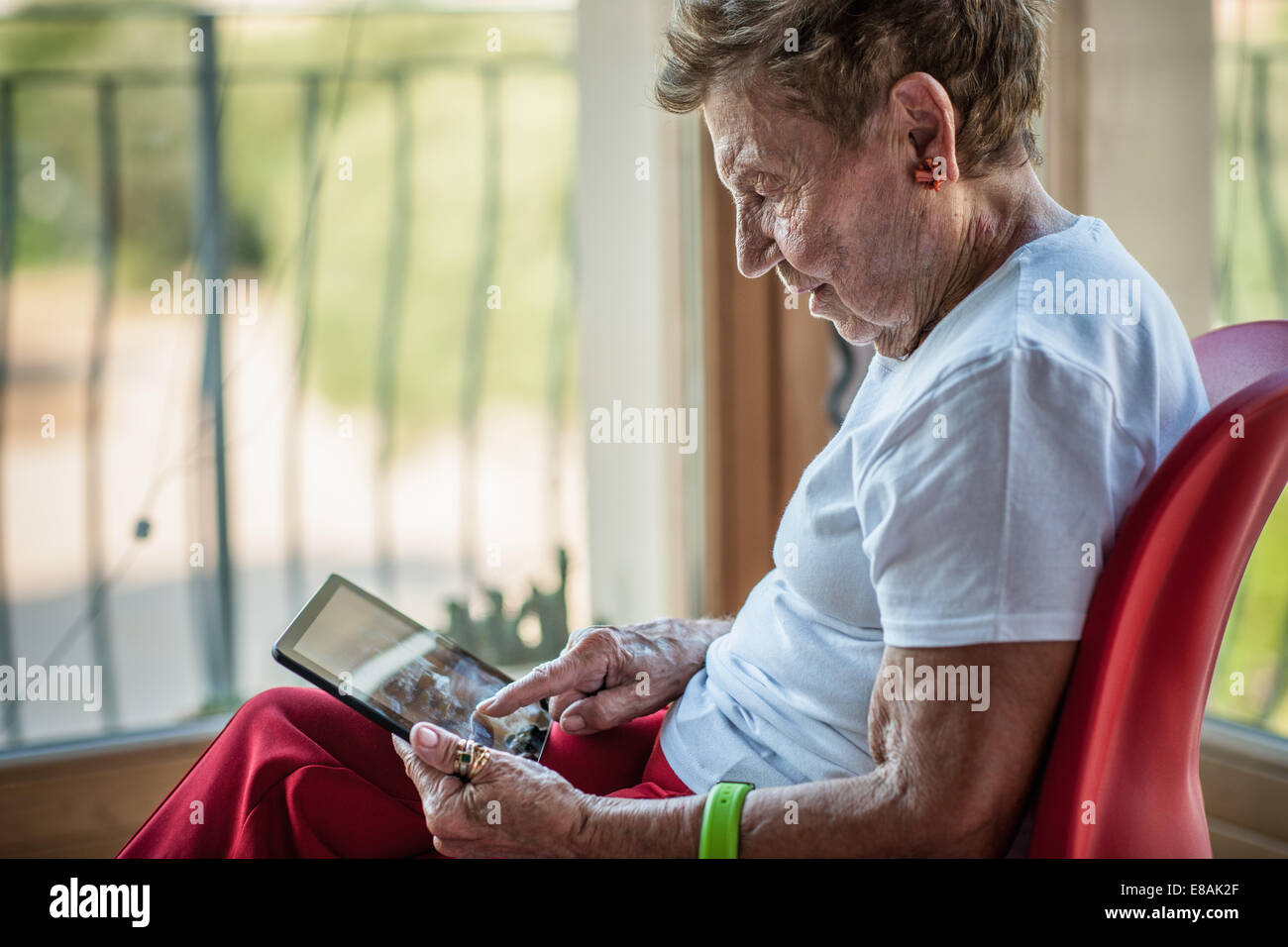A very senior woman using touchscreen on digital tablet on apartment ...