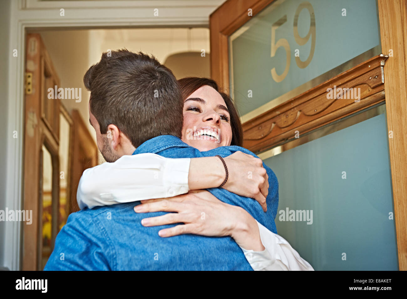 Couple hugging at front door Stock Photo - Alamy