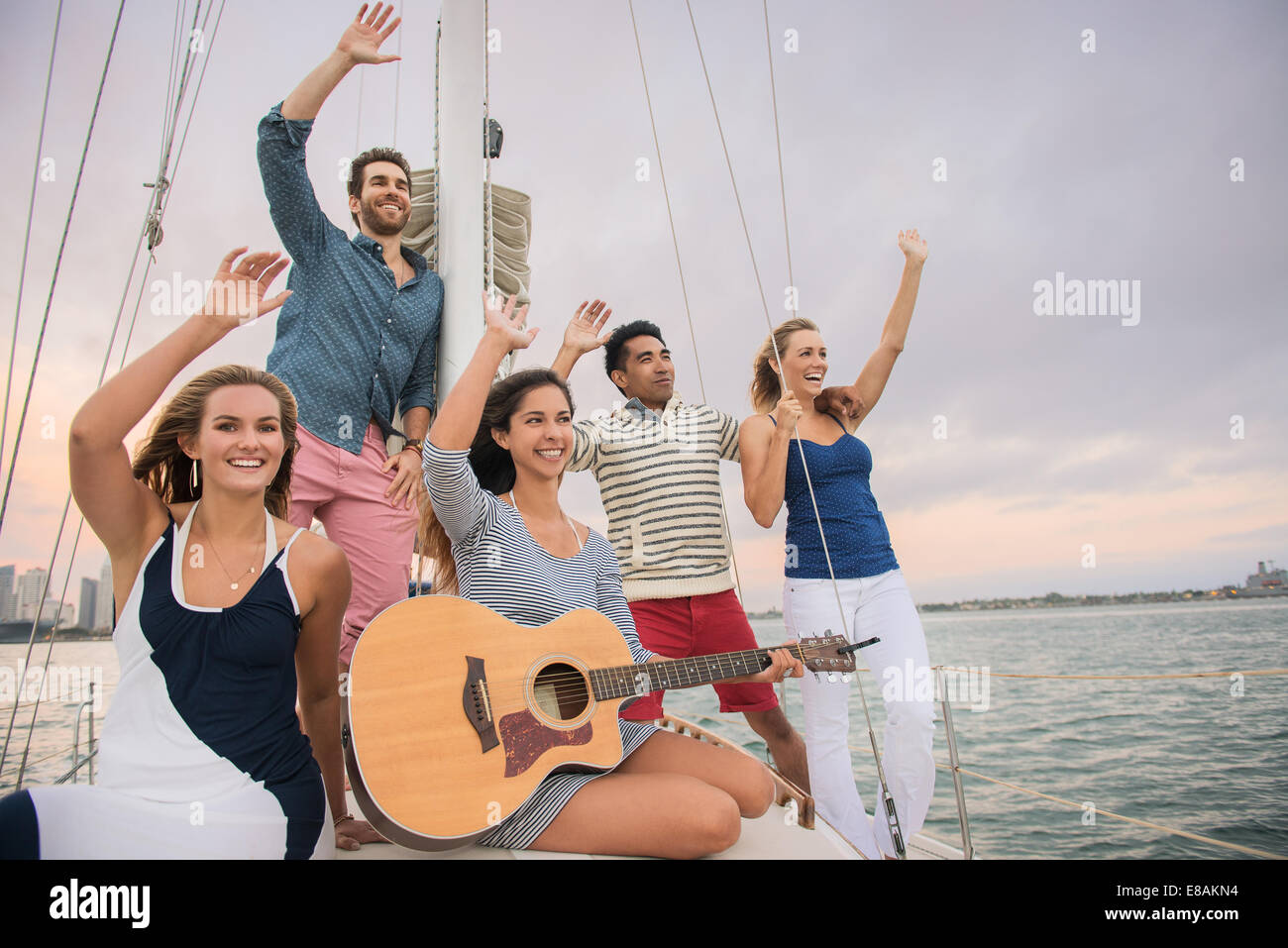Friends on sailing boat waving, woman with guitar Stock Photo - Alamy