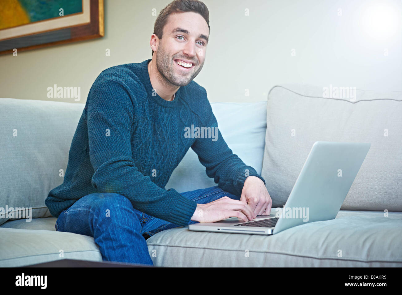 Man using laptop on sofa Stock Photo - Alamy