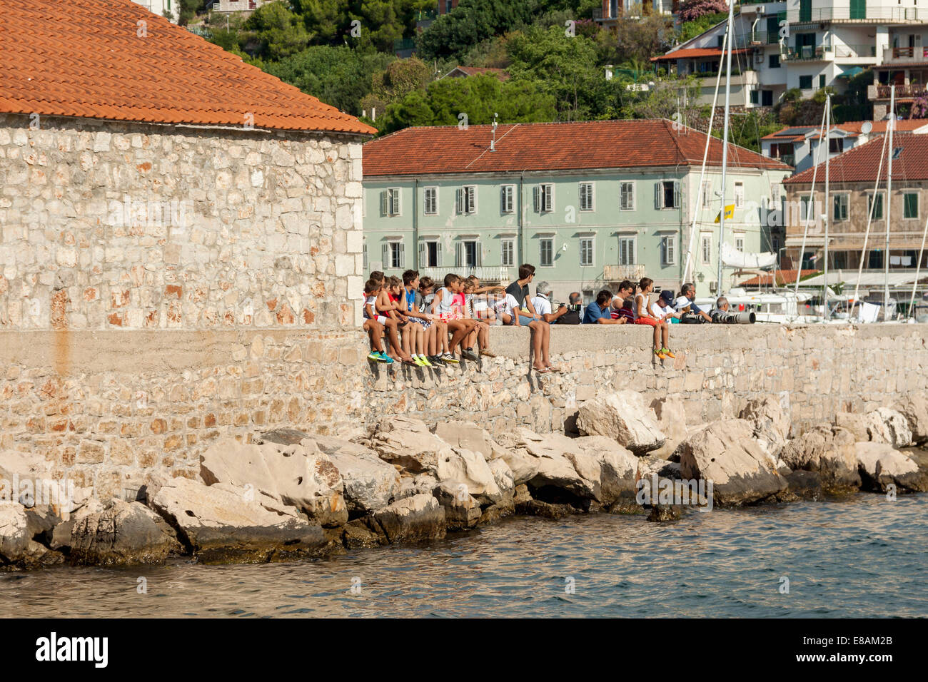 Children and tourists on a stone wall in Jelsa, Hvar island, Croatia ...