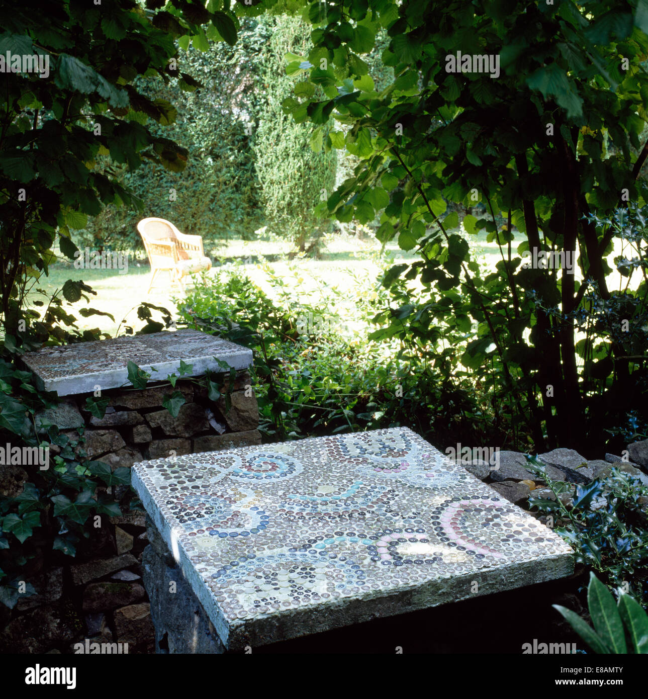 Mosaic tiles concrete table and seat in shady corner of country garden ...