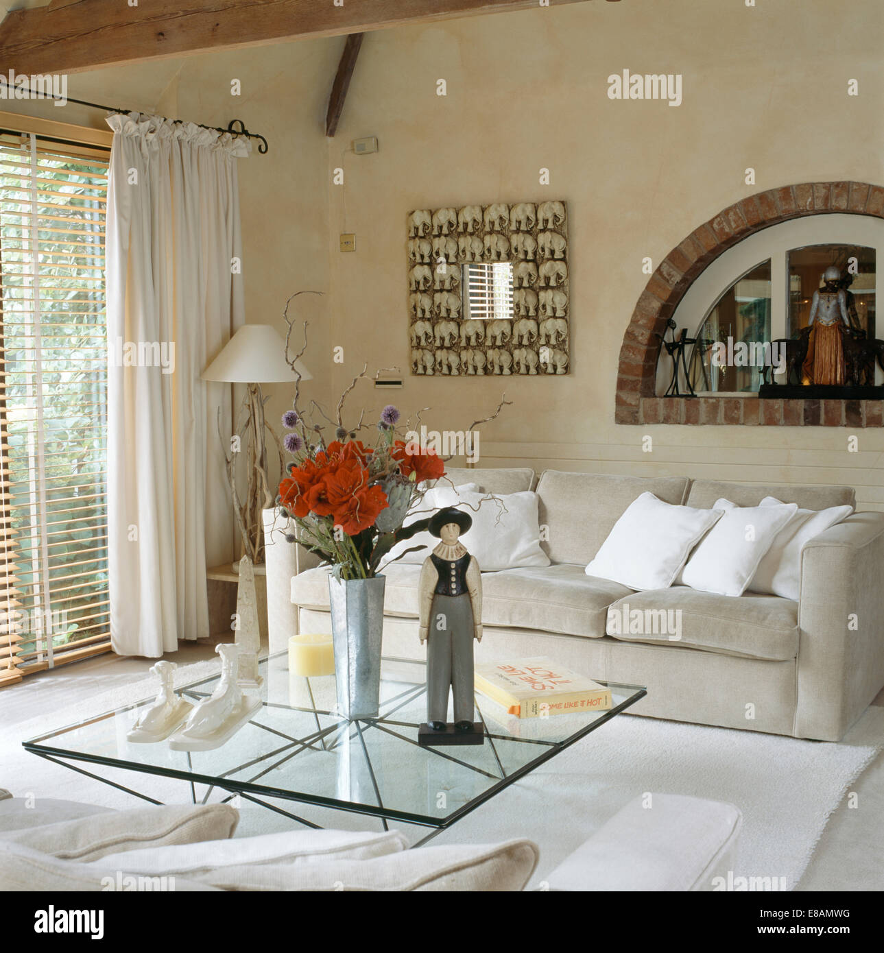 Wooden figure on glass coffee table in modern living room with arched ...