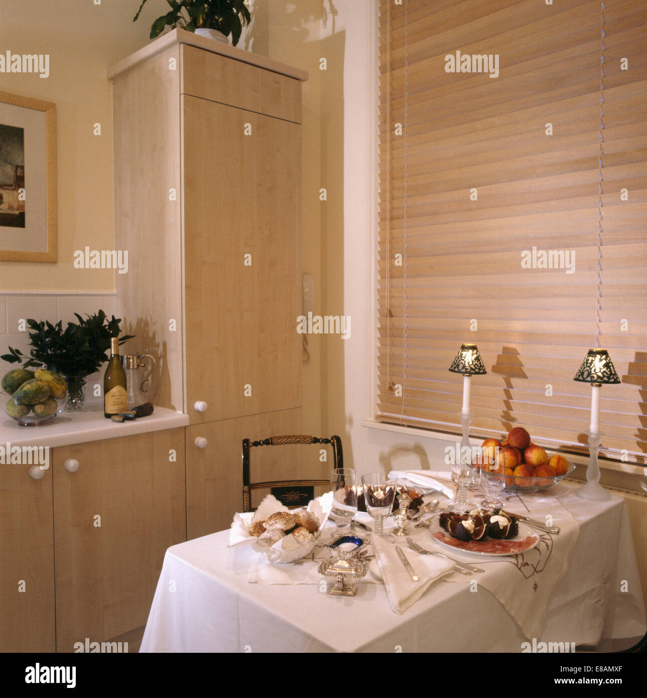 White cloth on table set for dinner in front of window with slatted ...