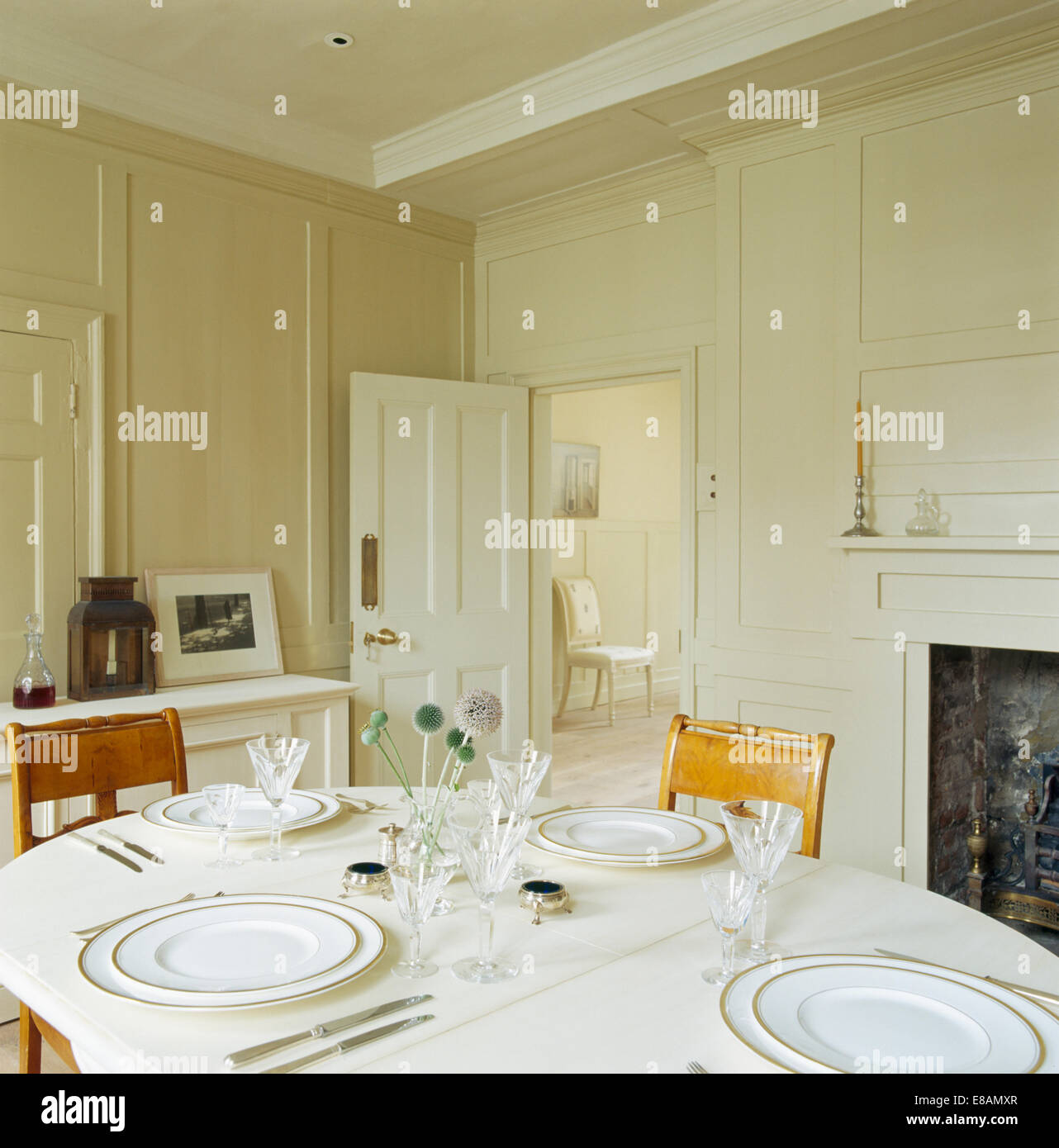 Traditional cream panelled dining room with white cloth on table set ...