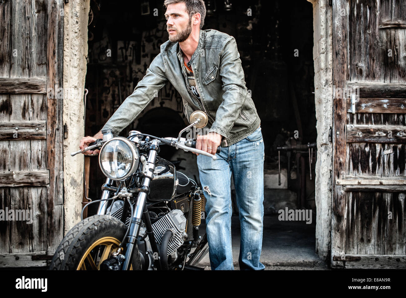 Mid adult man pushing motorcycle out of barn Stock Photo - Alamy