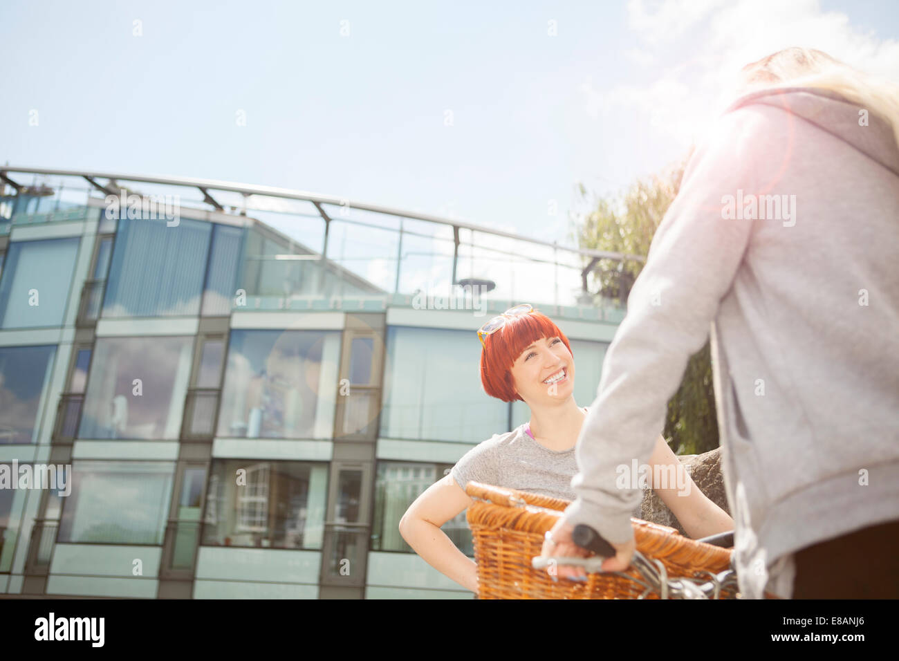 Friends chatting, glass-fronted building in background Stock Photo - Alamy