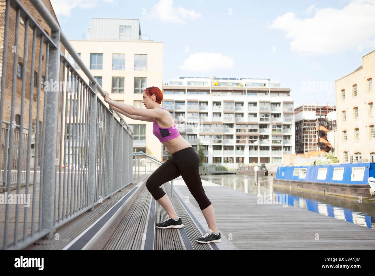Woman doing stretching exercise, building in background, East London ...