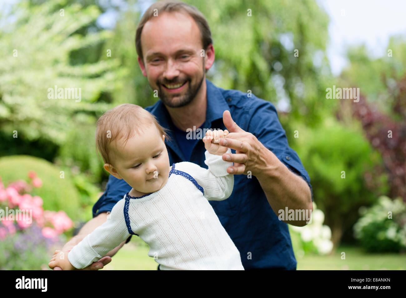 Father holding baby daughters hands whilst toddling Stock Photo - Alamy
