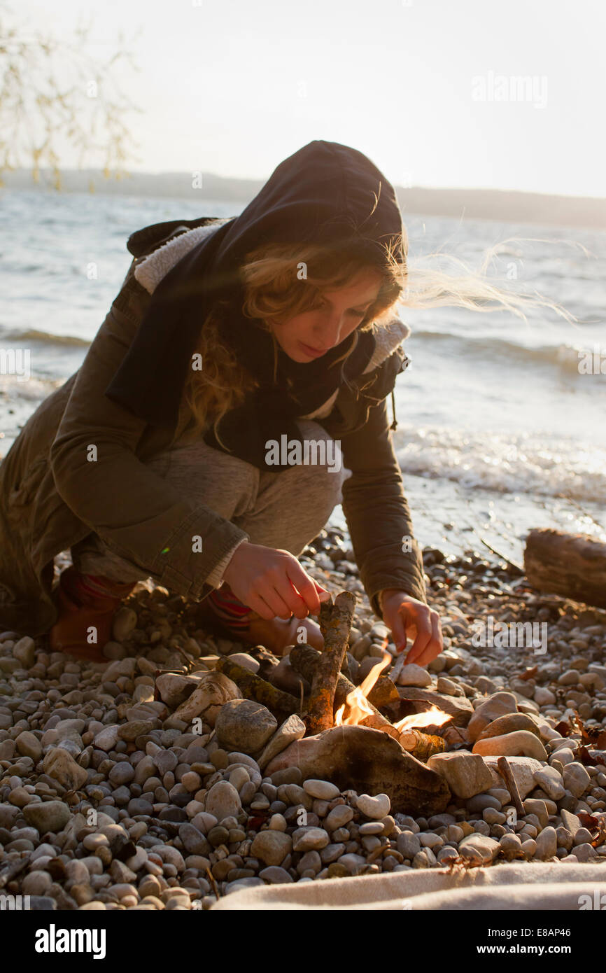 Woman making a fire by seaside Stock Photo - Alamy