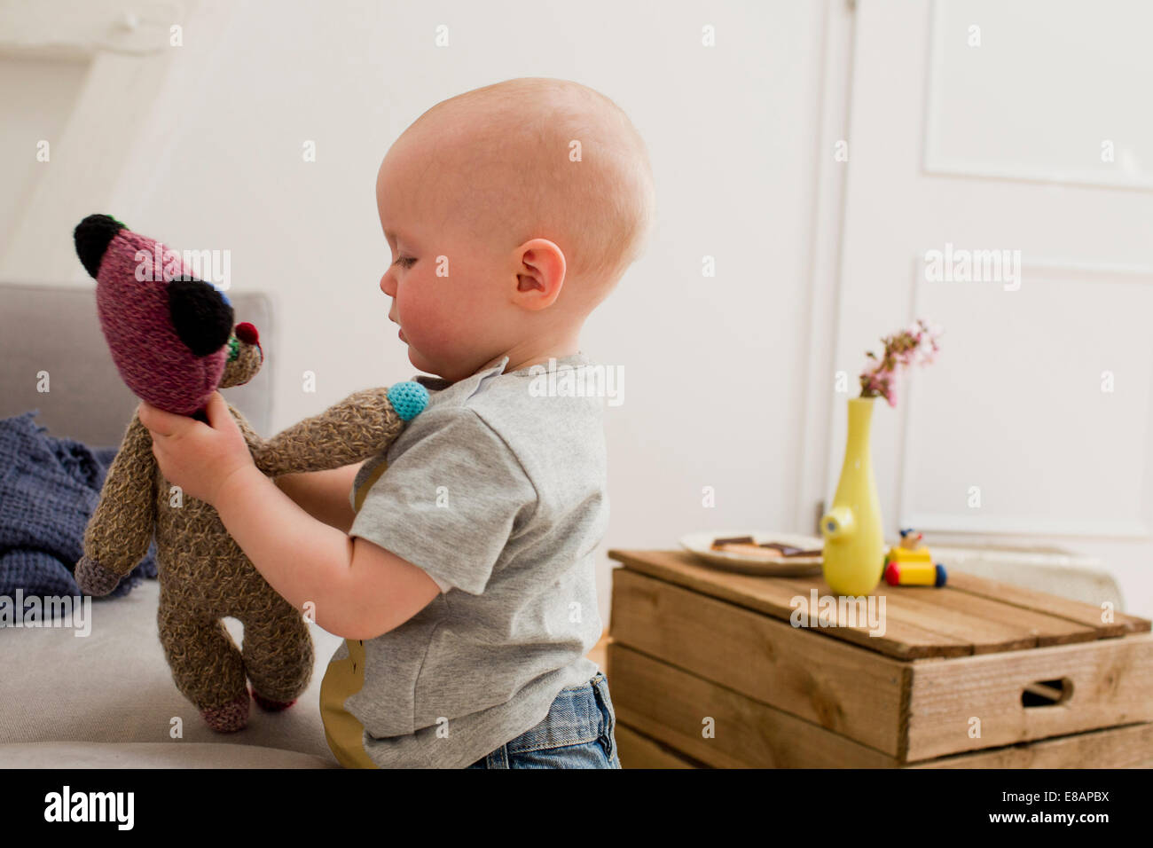 Baby girl pointing playing with teddy bear in sitting room Stock Photo ...