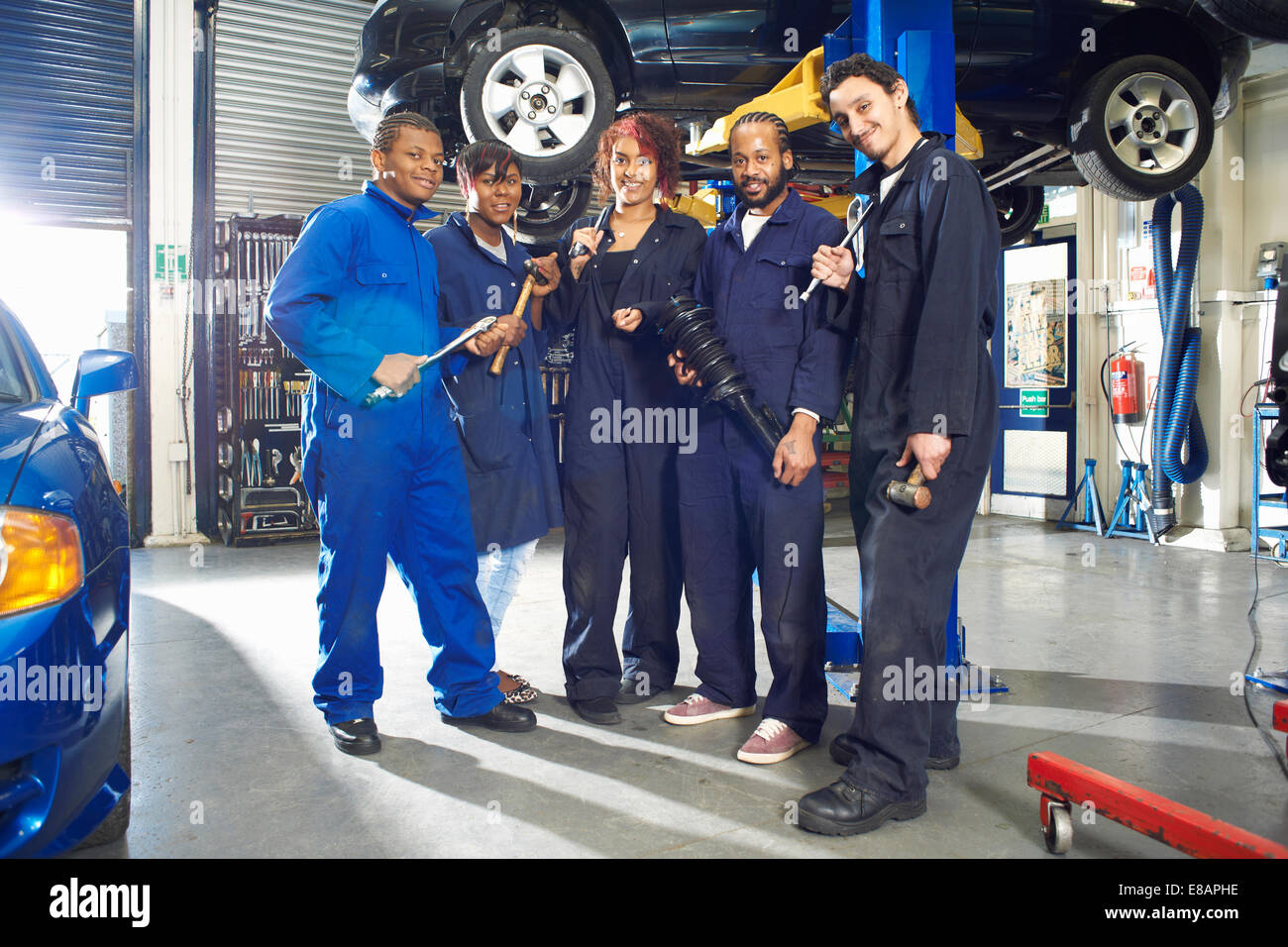 Portrait of five college students beneath car in garage workshop Stock ...
