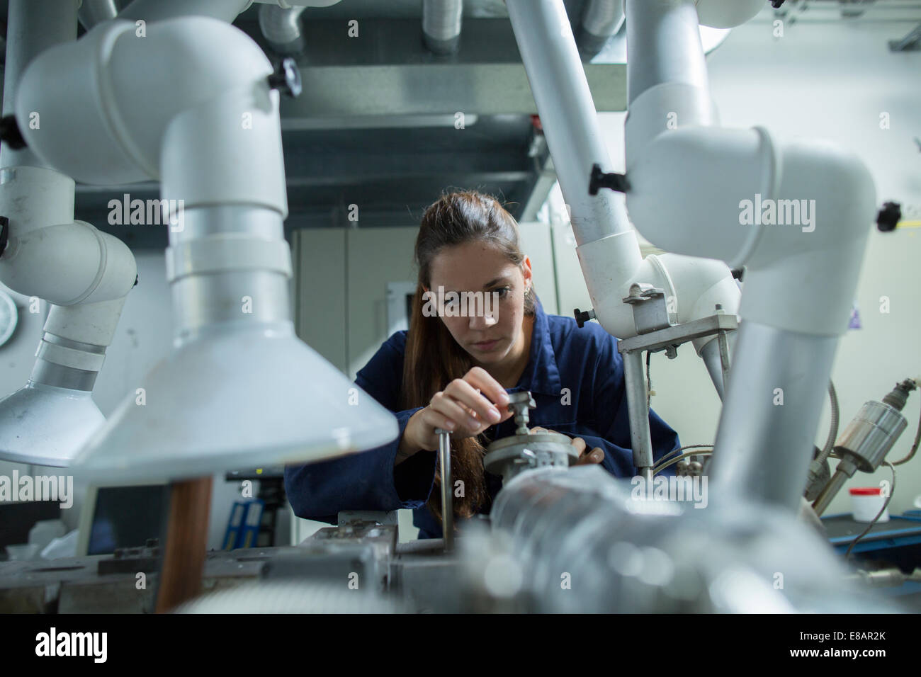 Female engineer turning pipe valves in factory Stock Photo - Alamy