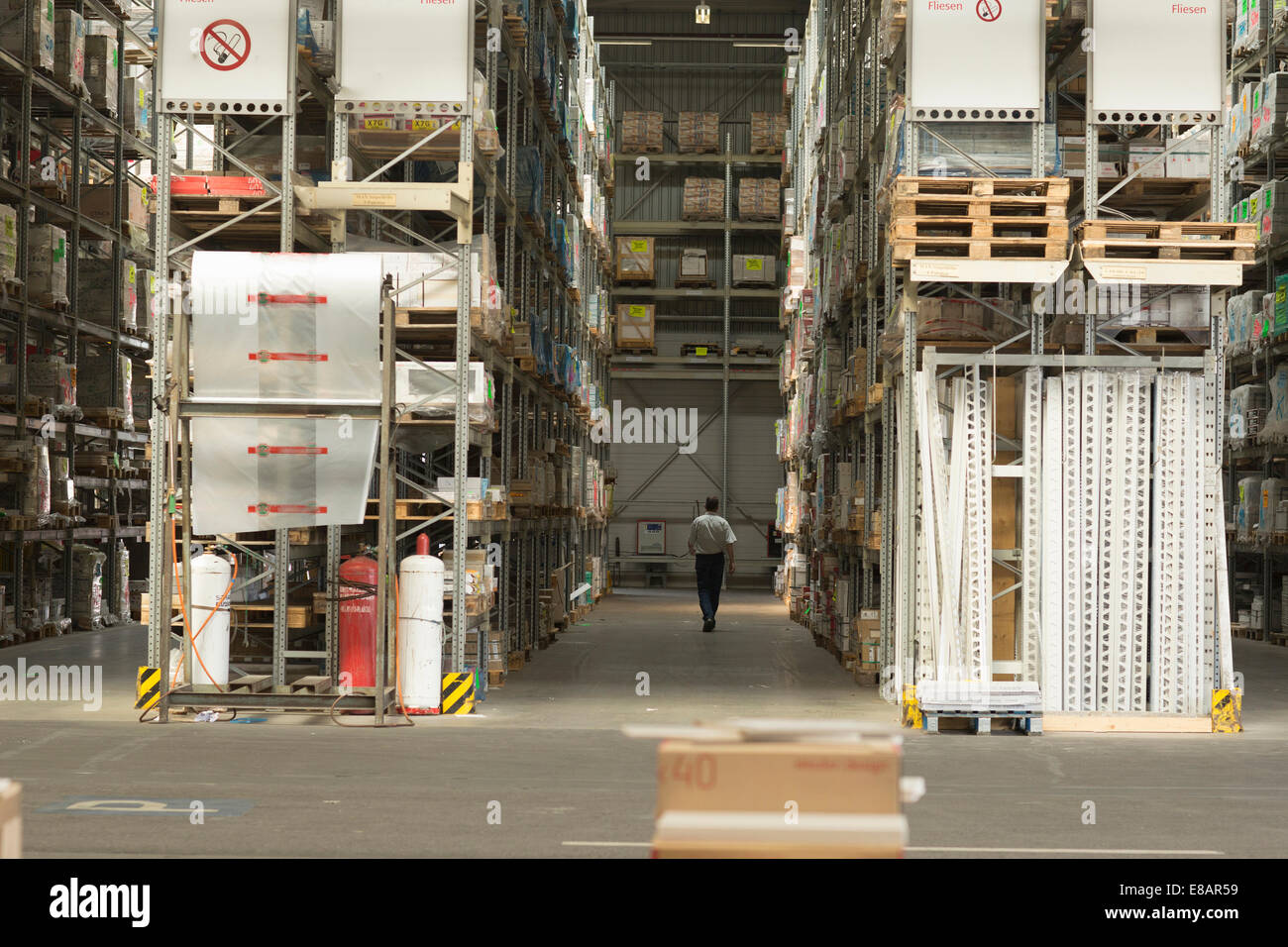 Worker searching for stock in aisles of hardware store warehouse Stock ...