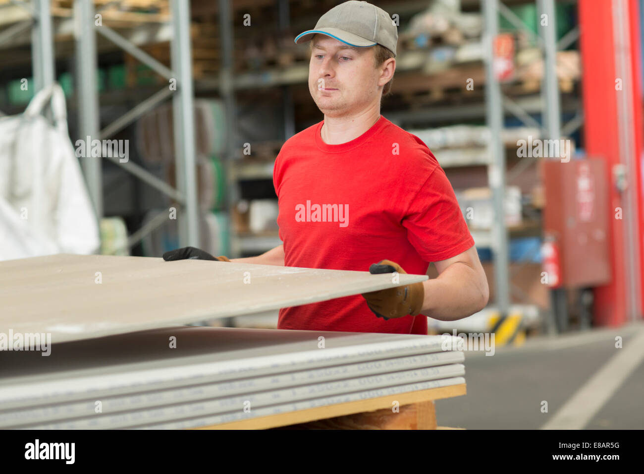 Worker lifting boards in hardware store warehouse Stock Photo - Alamy