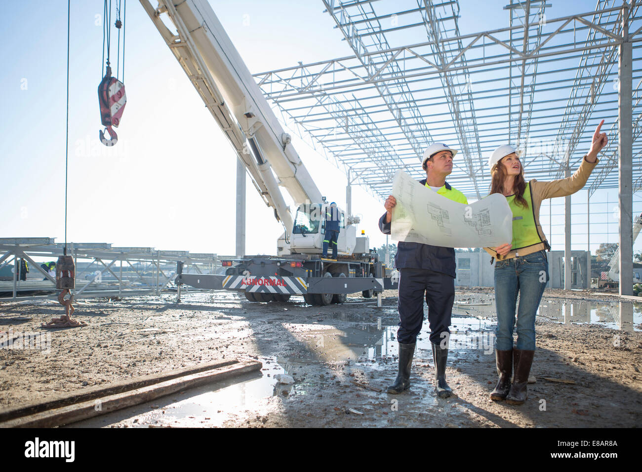Site manager and architect checking blueprint on construction site ...
