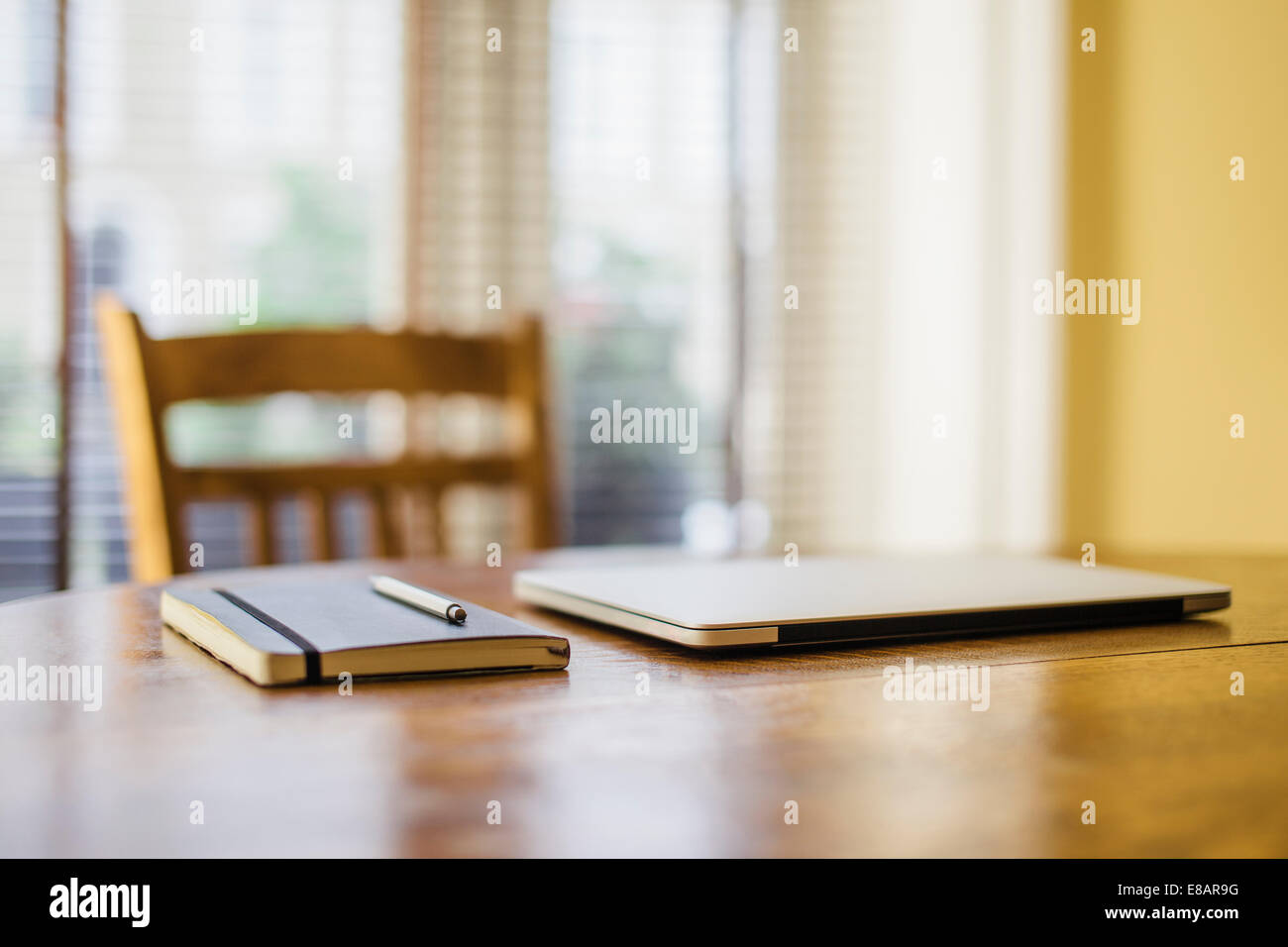 Notebook pen and laptop on dining room table Stock Photo - Alamy