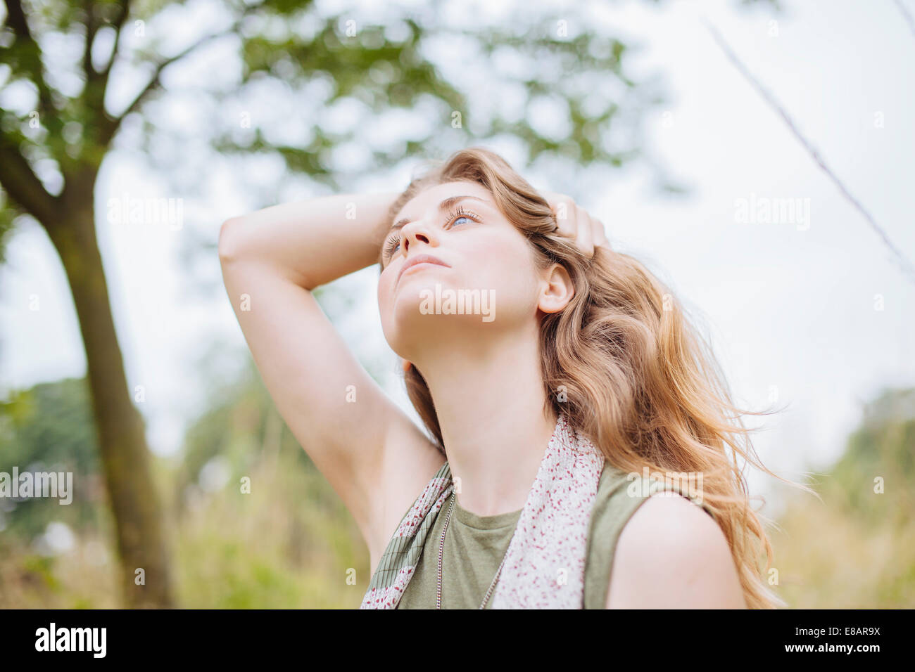 Serene young woman gazing up with hand in hair Stock Photo - Alamy