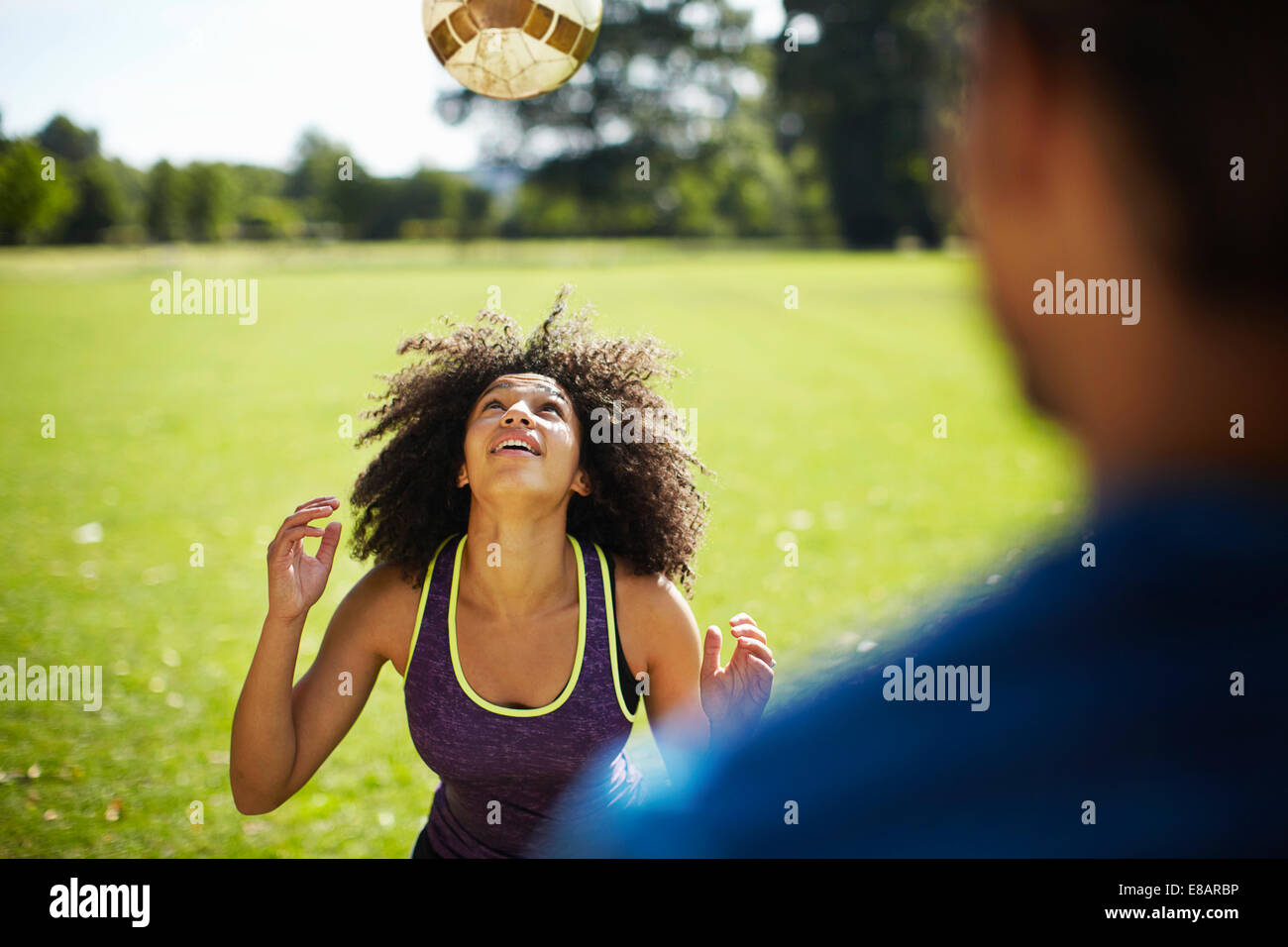 Young woman heading football in park Stock Photo - Alamy