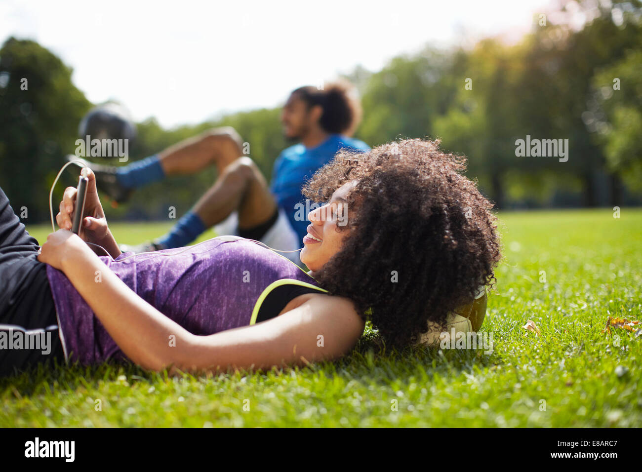 Young woman taking a break reading texts on smartphone in park Stock ...