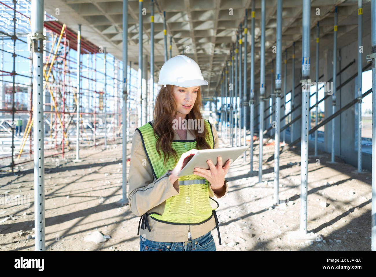 Site manager using touchscreen on digital tablet on construction site ...