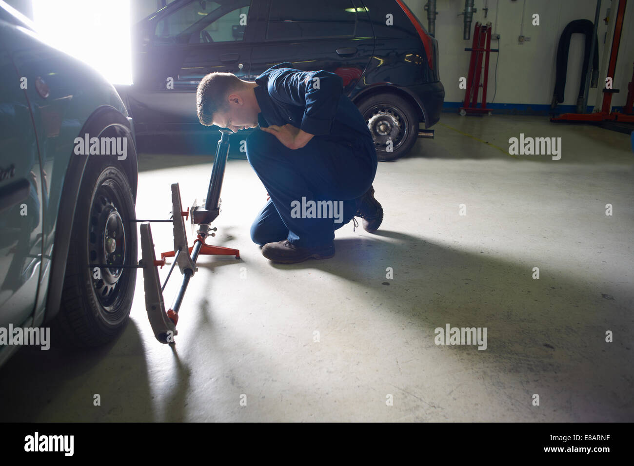 Male student mechanic checking car wheel in college garage Stock Photo ...