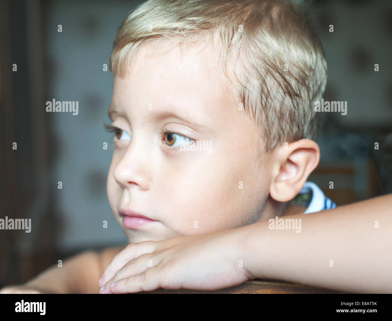 Beautiful cute young boy thinking sitting on chair Stock Photo - Alamy