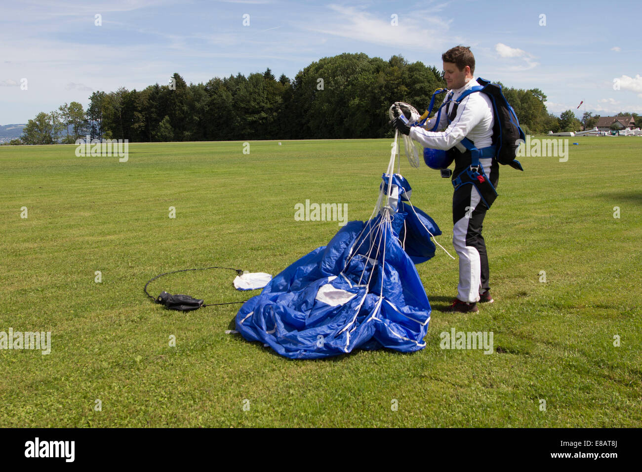 Male skydiver folding his parachute after skydive landing, Buttwil ...