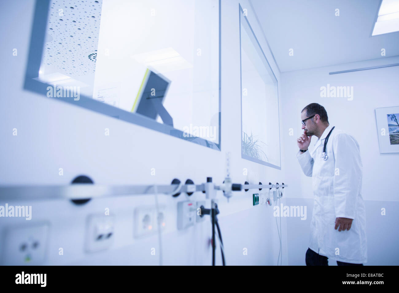 Doctor watching through treatment room window in hospital Stock Photo ...