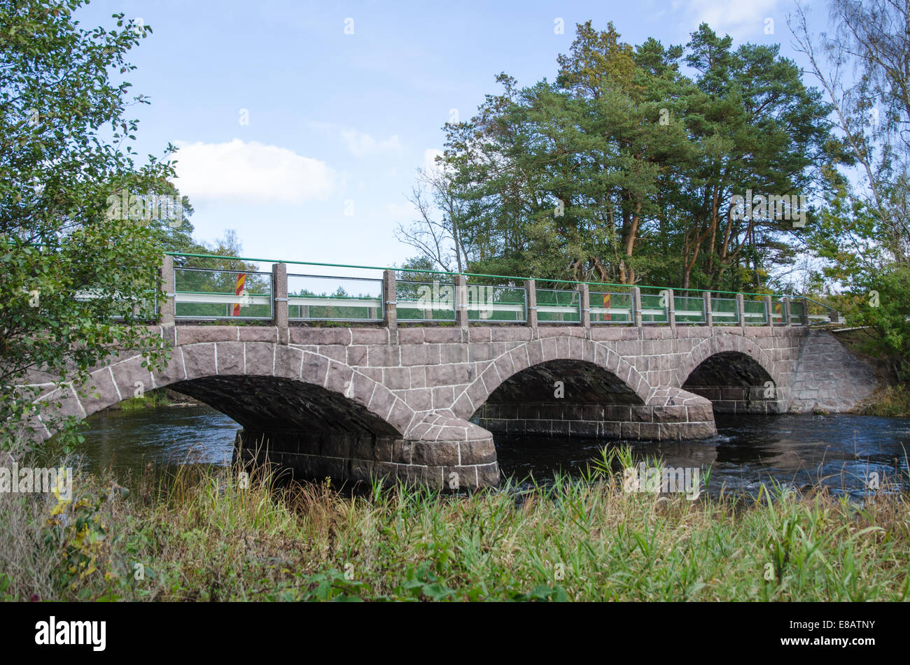 Old bridge with arches over a small river in a green landscape Stock ...