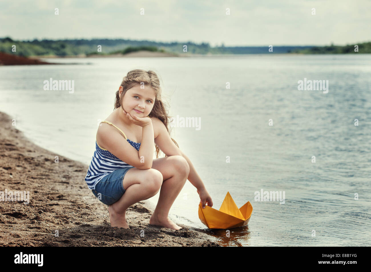 Cute girl posing with homemade paper boat by lake Stock Photo - Alamy