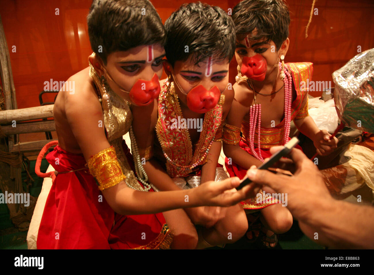 Children artist look at their photograph in a mobile phone as they will perform as Vanar Sena or ...