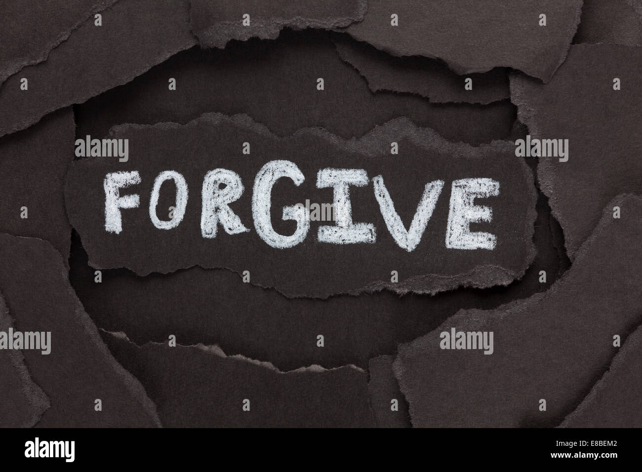Forgive. Torn pieces of black paper and the word "Forgive". Close-up ...