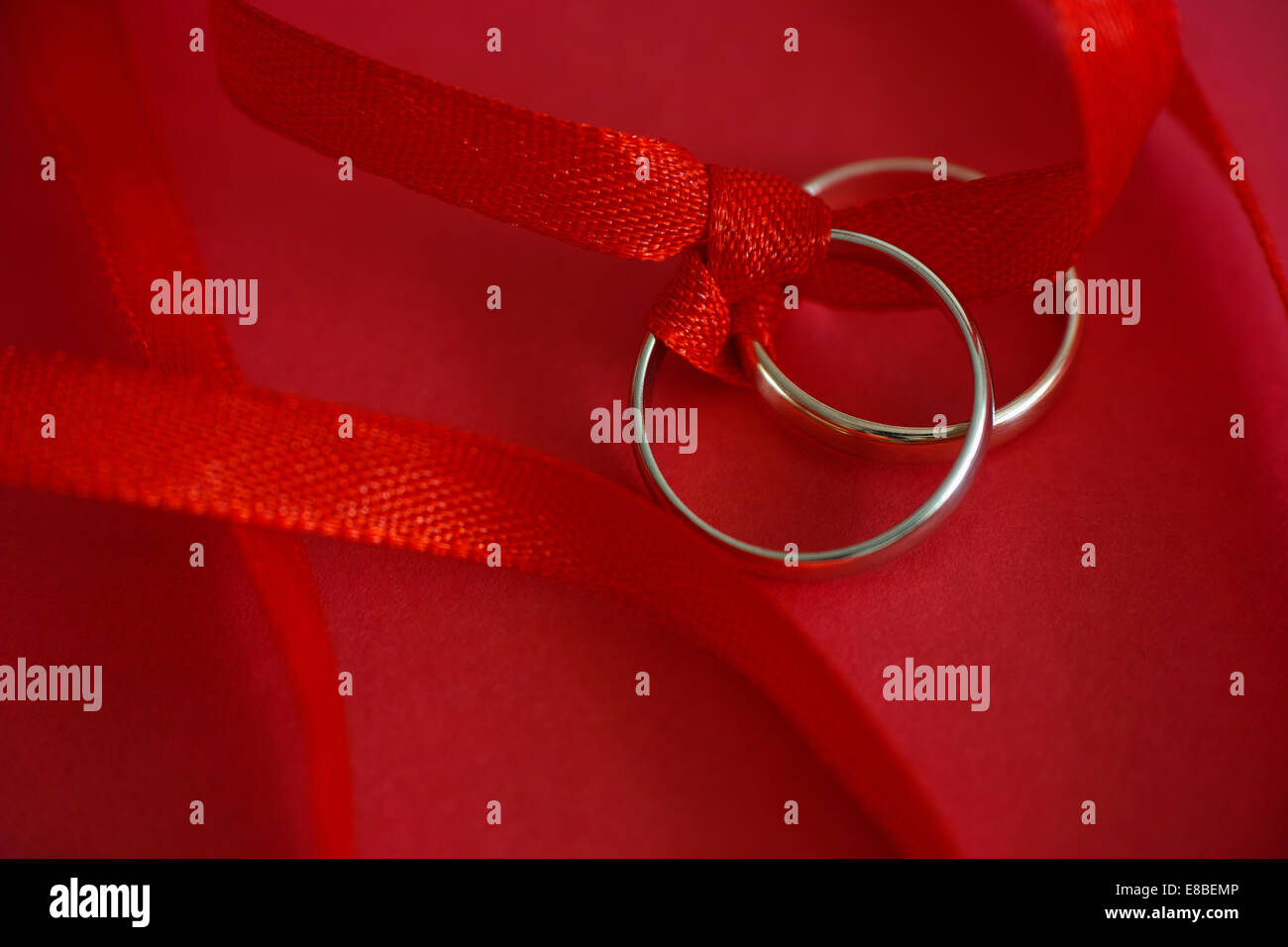 Wedding rings with red ribbon on red background. Close-up Stock Photo ...