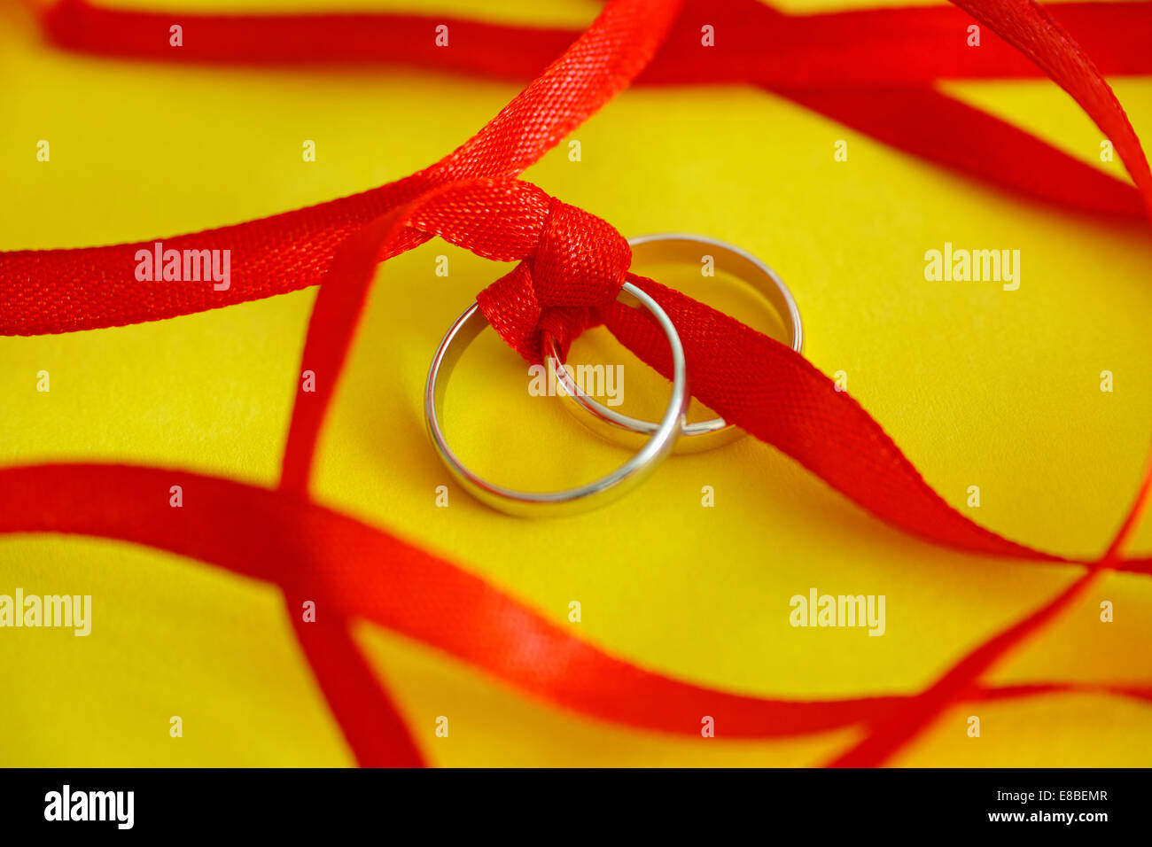 Wedding rings with red ribbon on yellow background. Close-up Stock ...