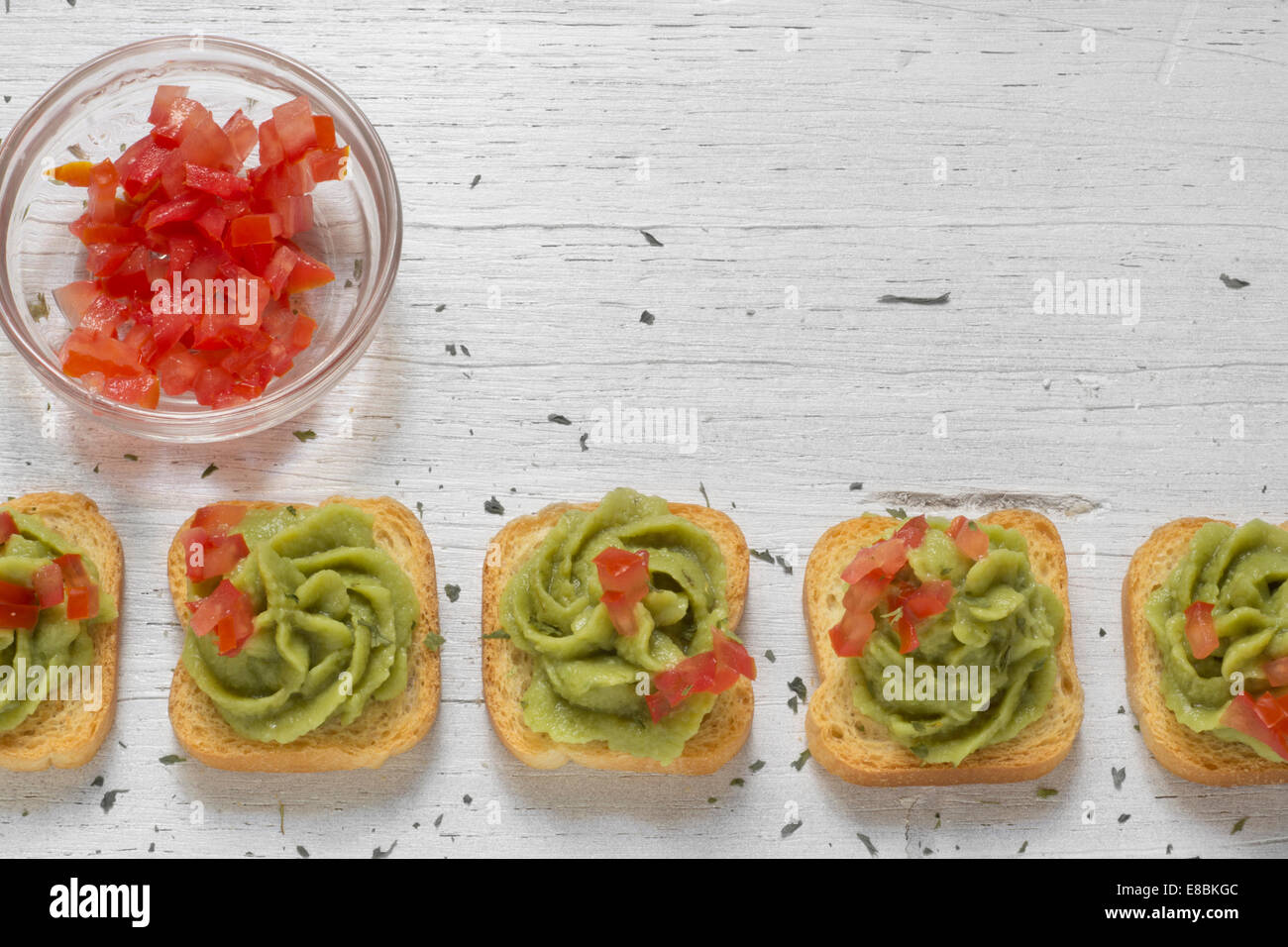 Mini-toast, decorated with guacamole, chopped tomato, white wooden ...