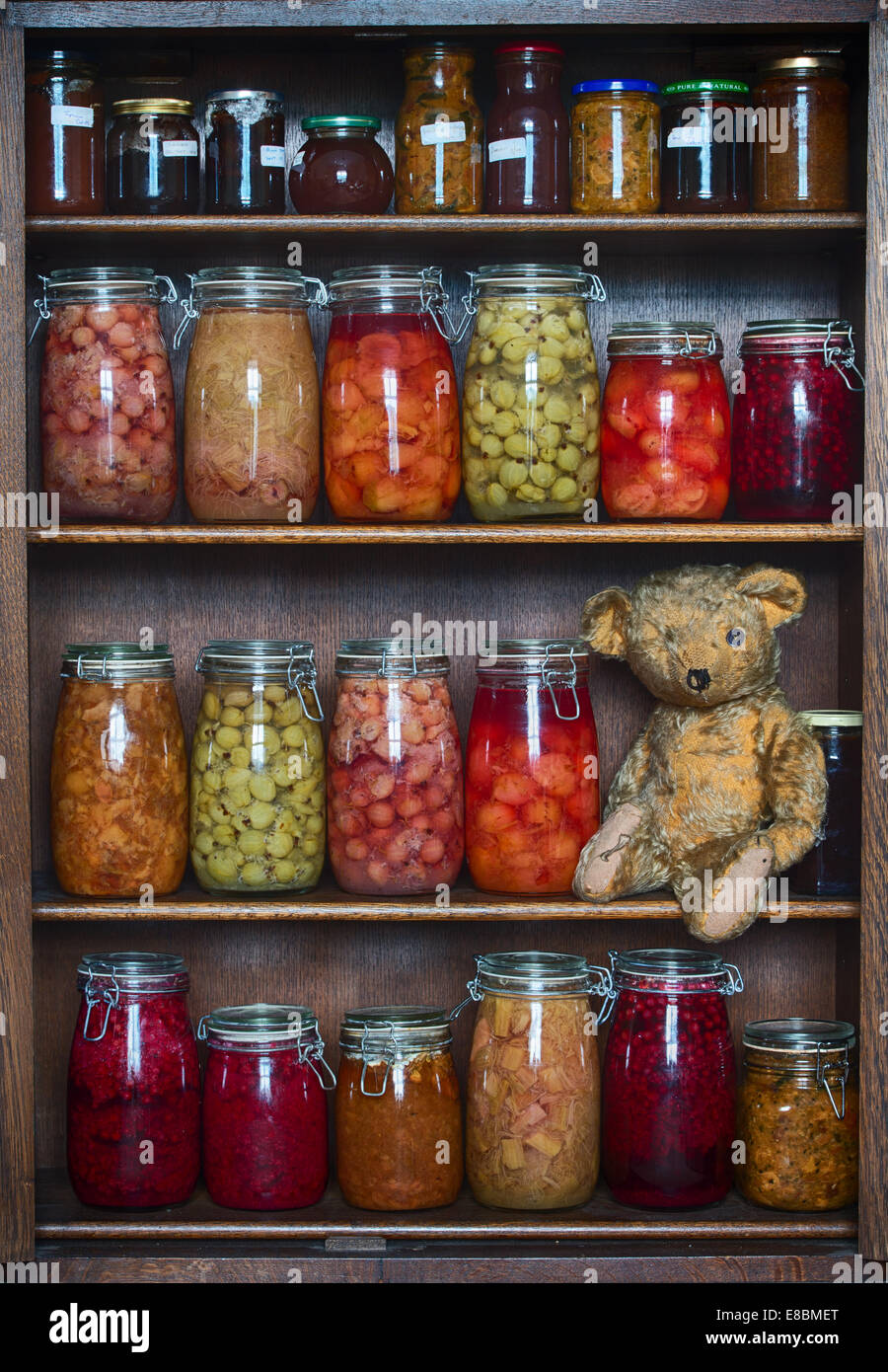 Threadbare One Eyed Teddy bear on a wooden shelf with stored bottled ...