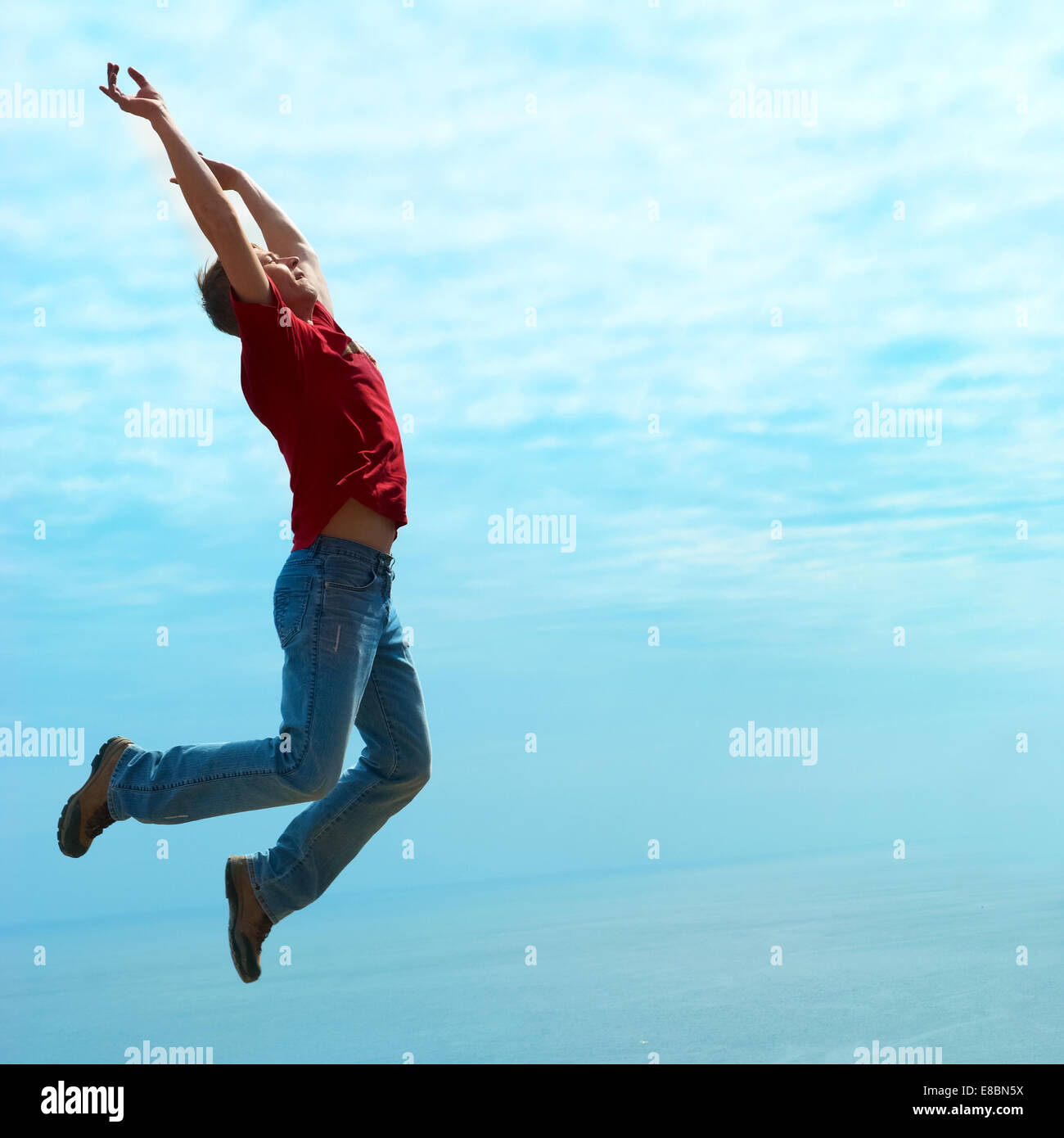 Jumping man against sea with blue sky and clouds Stock Photo - Alamy