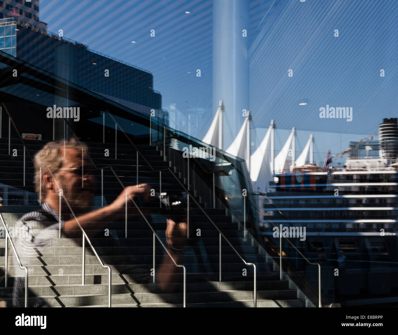 A male tourist with a camera taking a picture; the reflection of BC ...