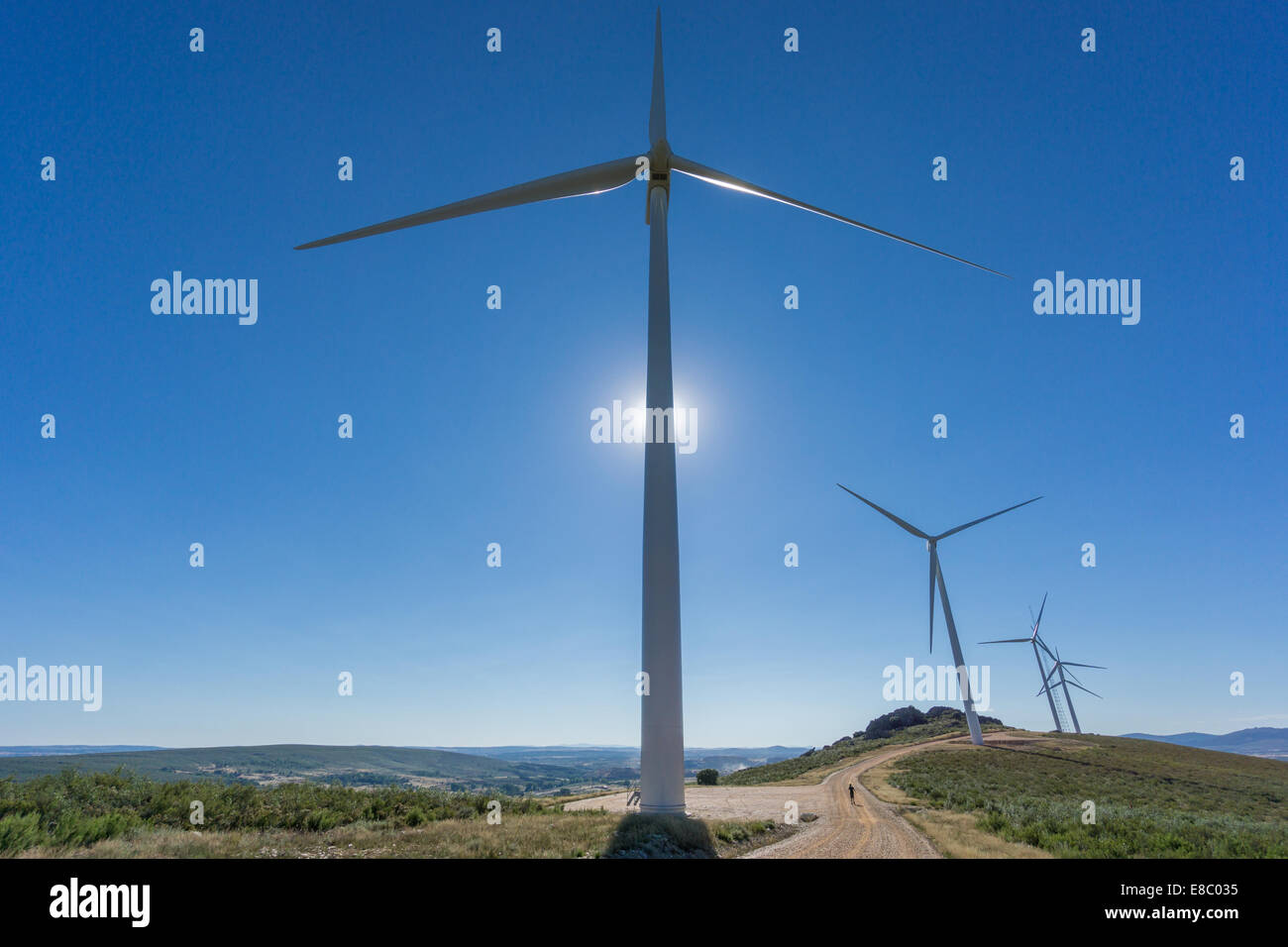 Backlit of Wind turbines, track and rocks in the countryside Stock ...