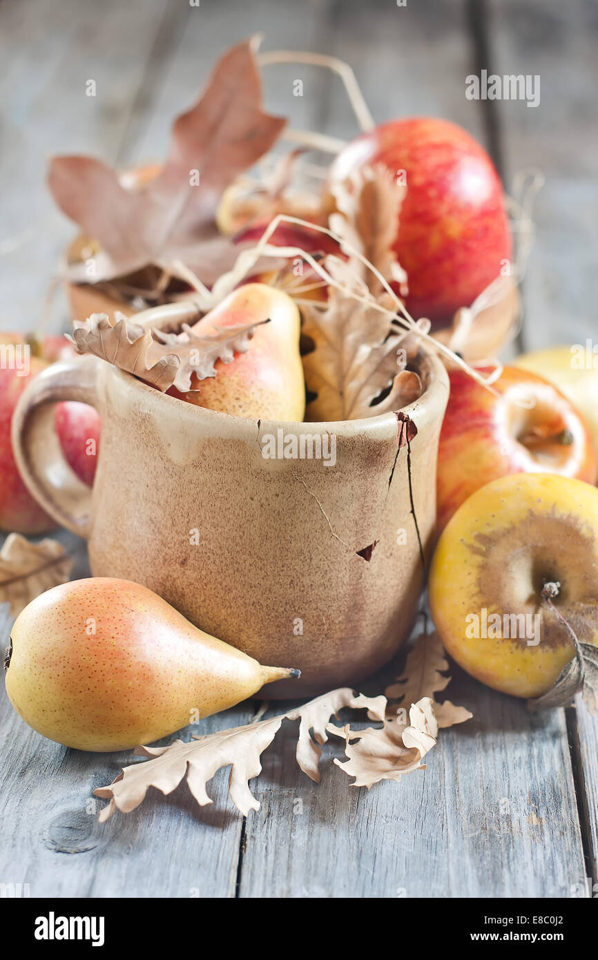 Ripe pears and apples with dry fall leaves on wooden background ...