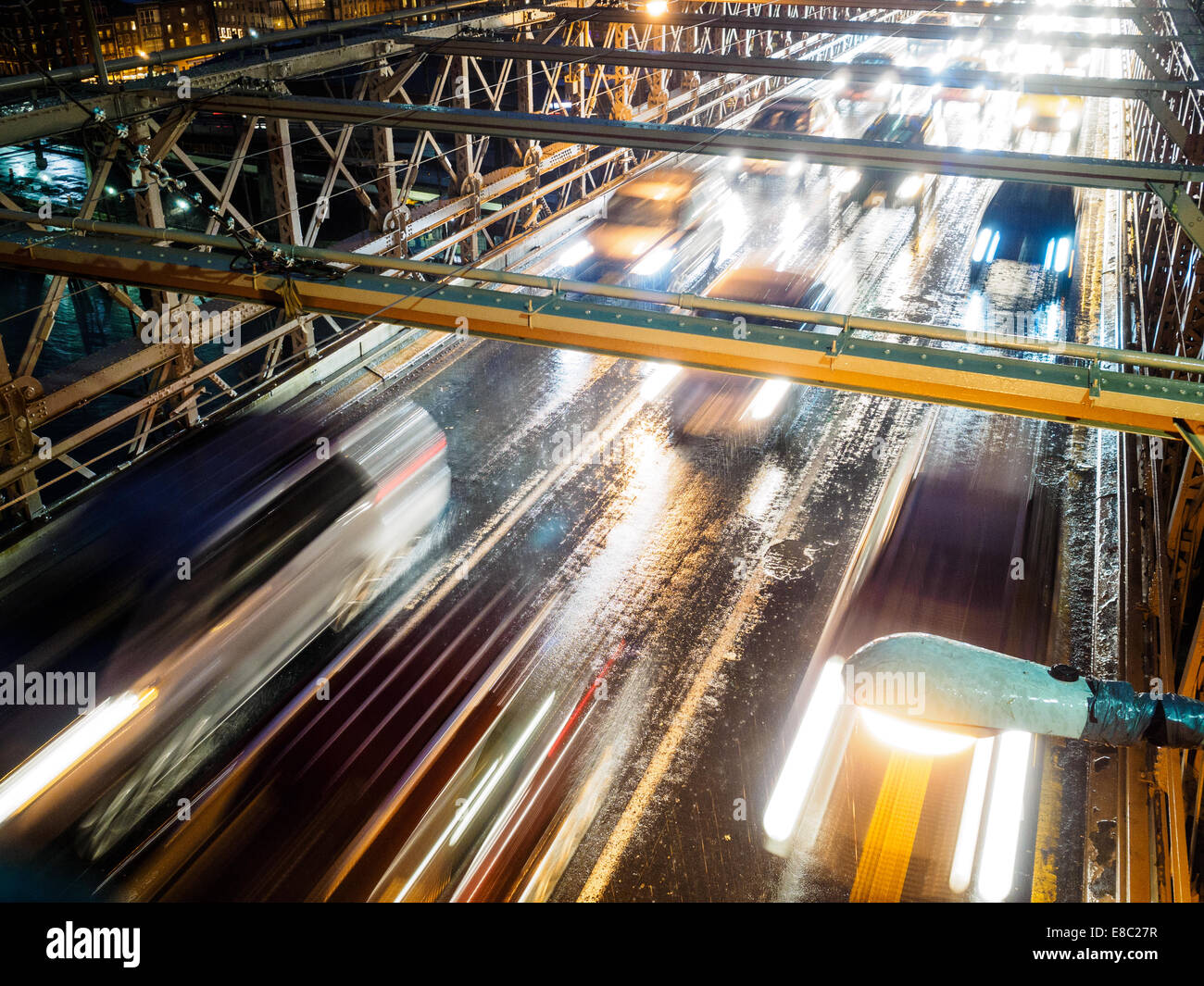 Traffic over Brooklyn Bridge at night in the rain, cars blurred due to ...
